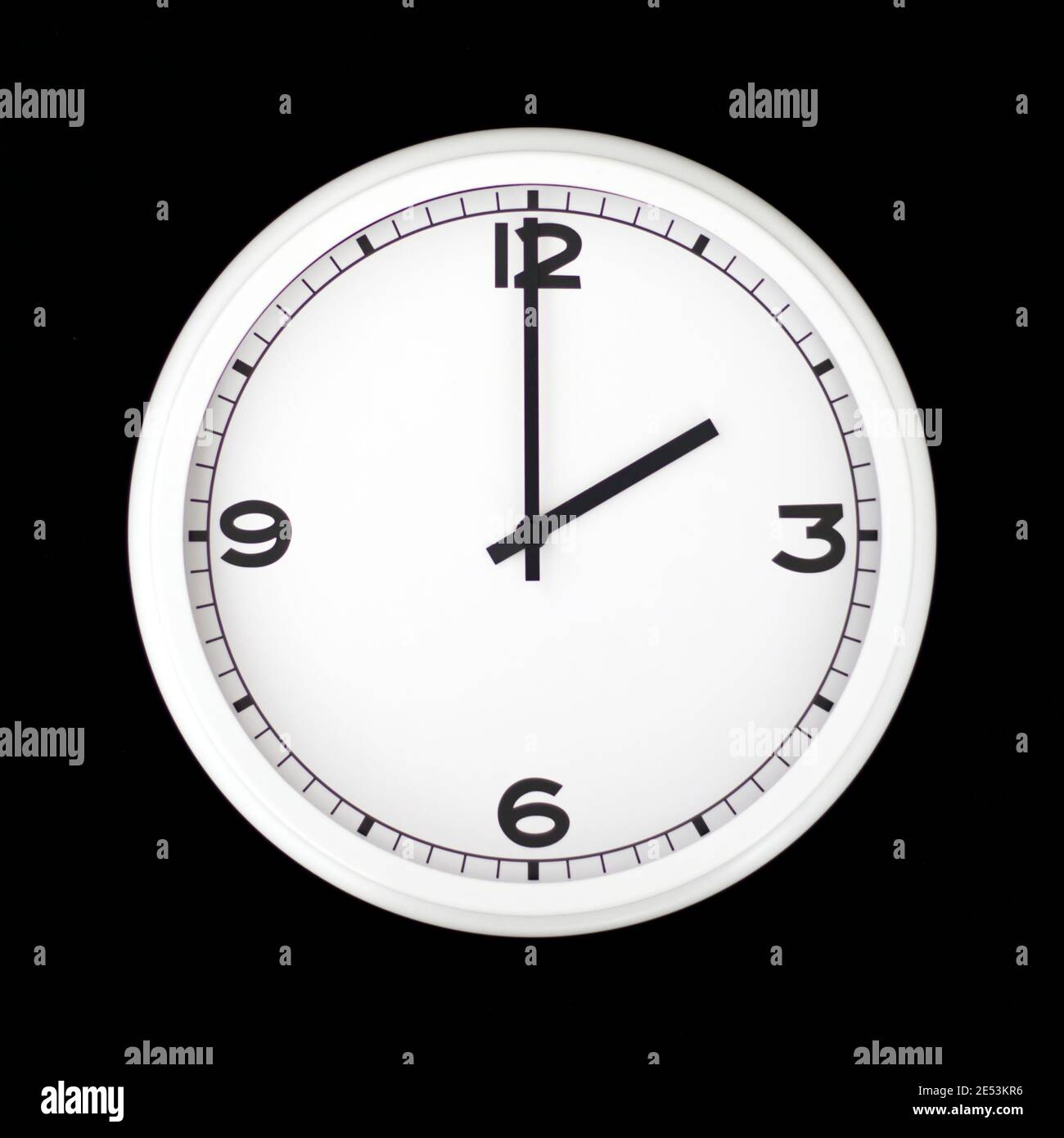 White round analog wall clock isolated on black background, its two ...