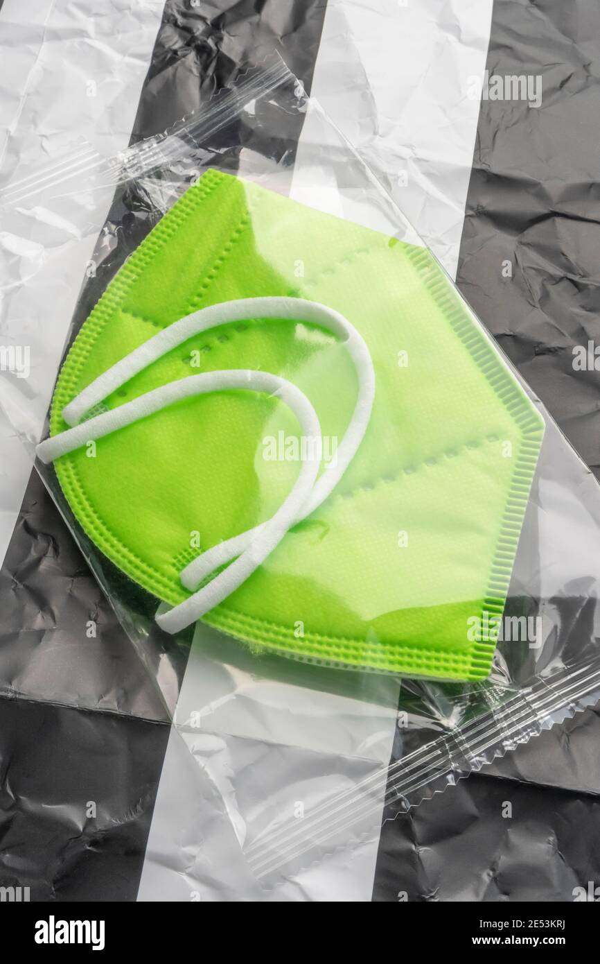 New green respirator FFP2, KN95 in plastic packaging on striped ...
