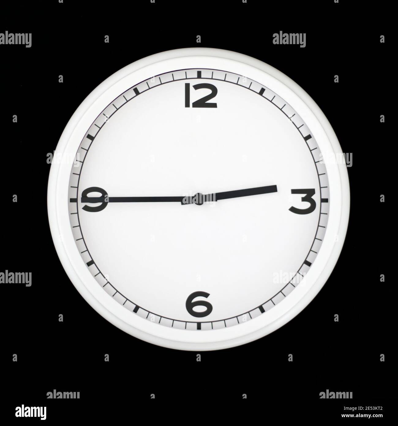 White round analog wall clock isolated on black background, its quarter ...
