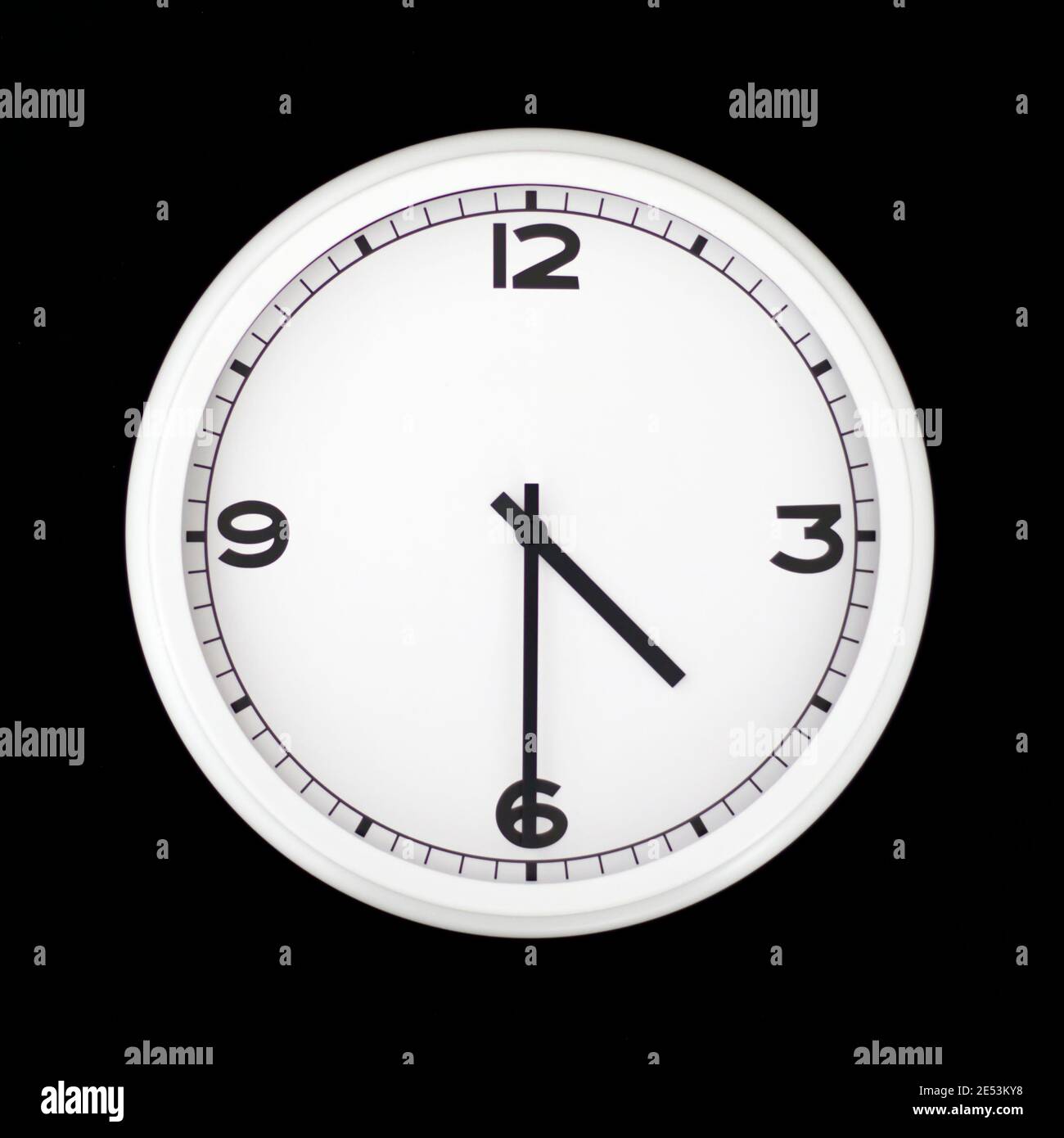 White round analog wall clock isolated on black background, its half ...