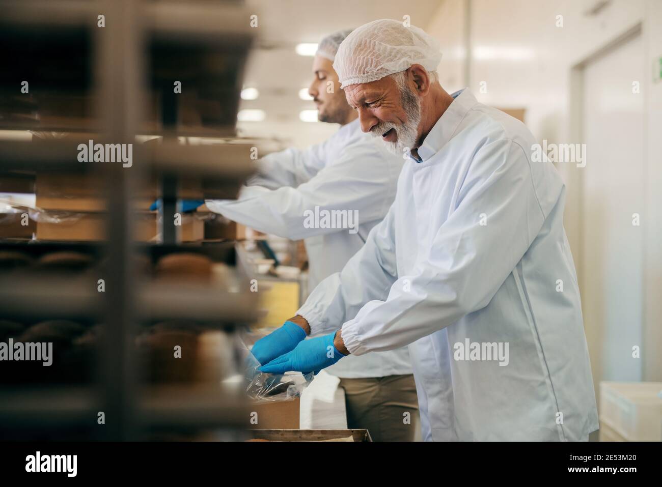 Workers packing cookies in boxes while standing in food factory Stock ...