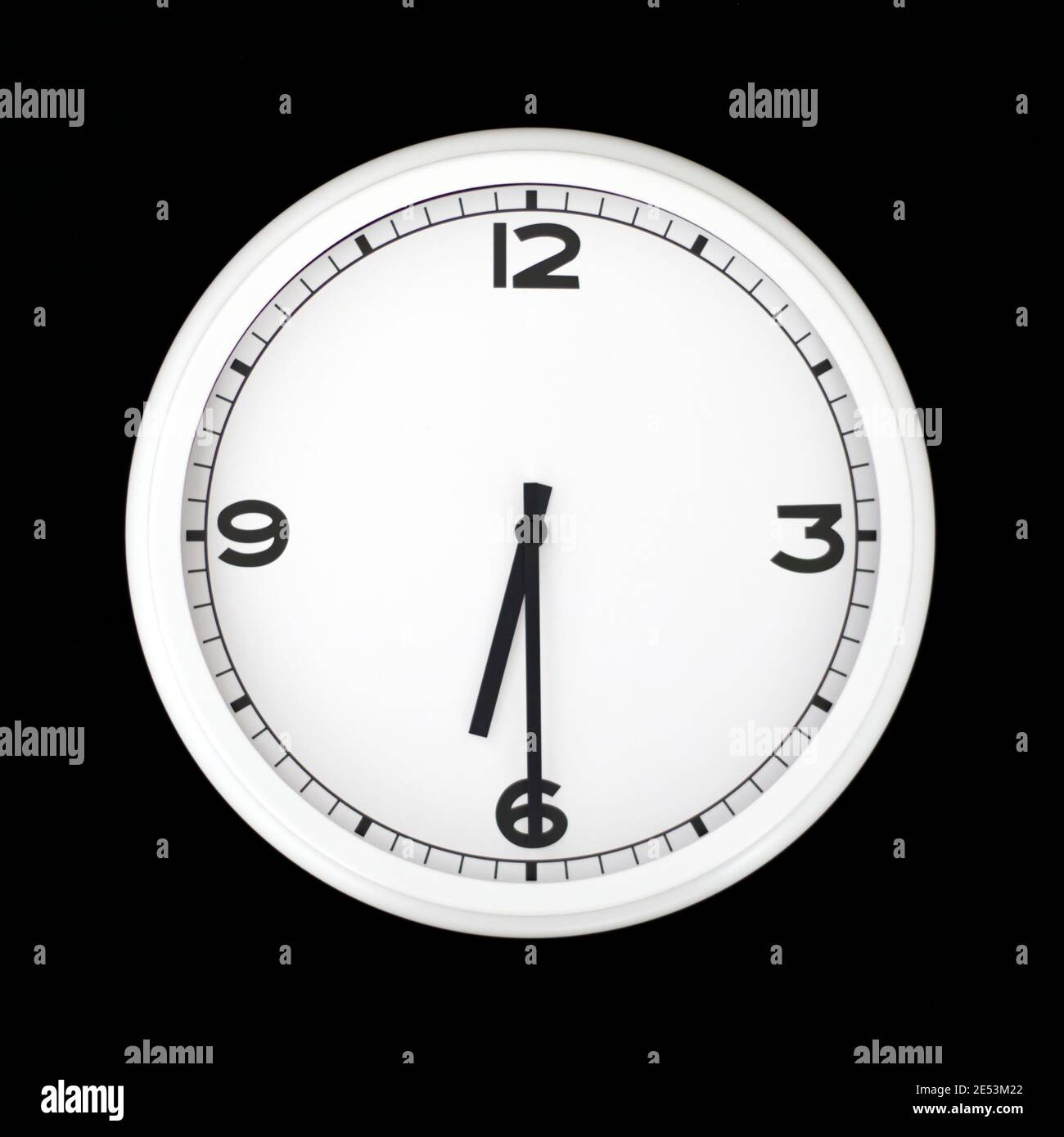 White round analog wall clock isolated on black background, its half ...