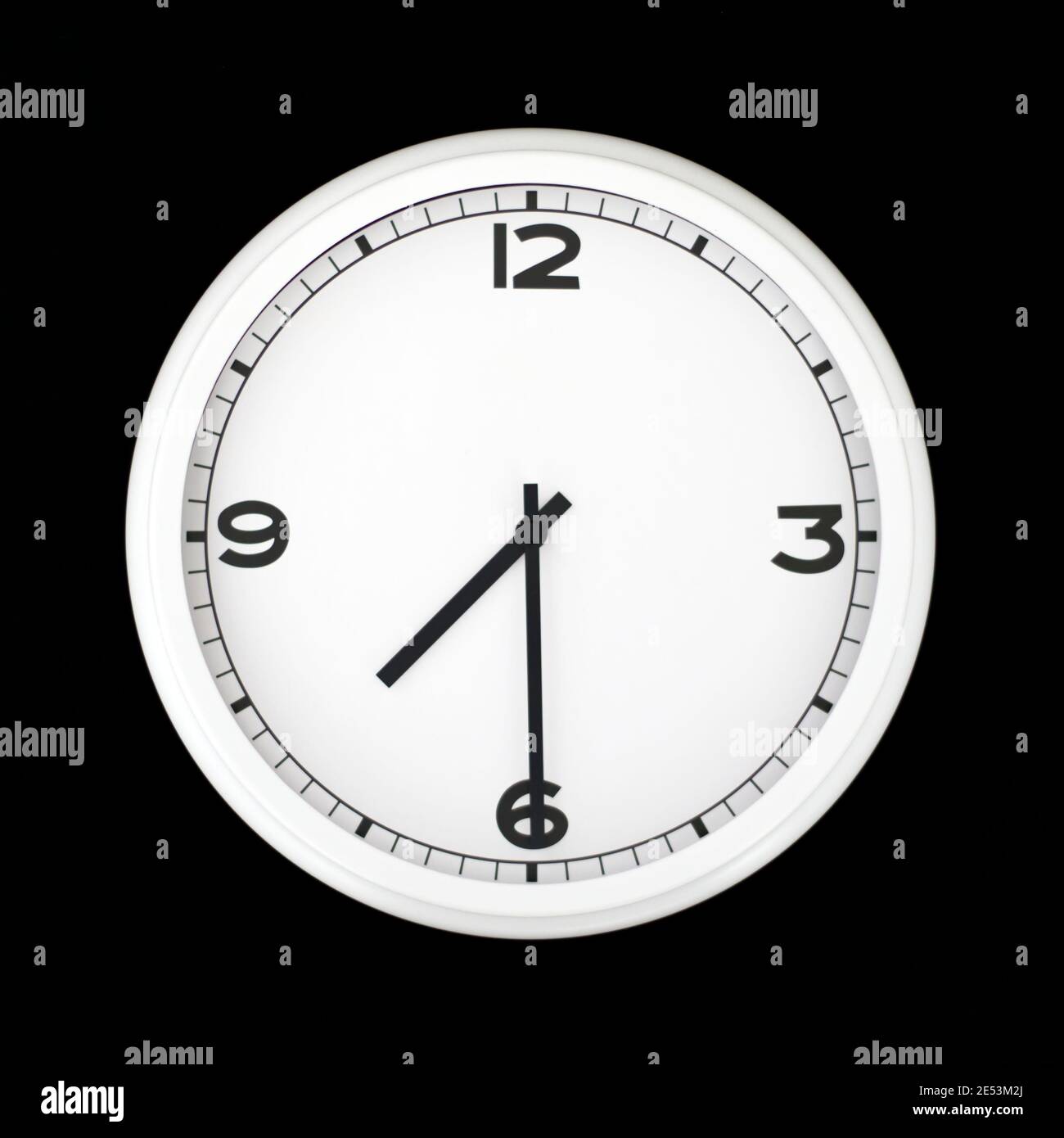 White round analog wall clock isolated on black background, its half ...