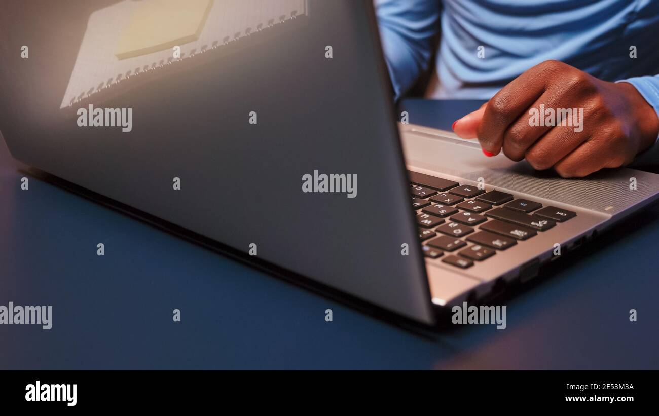 Close up of black woman typing on keyboard of laptop sitting at desk in ...