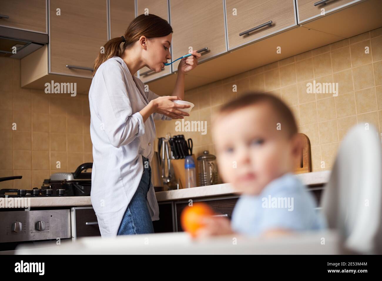 Careful woman trying soup before feeding her son Stock Photo - Alamy