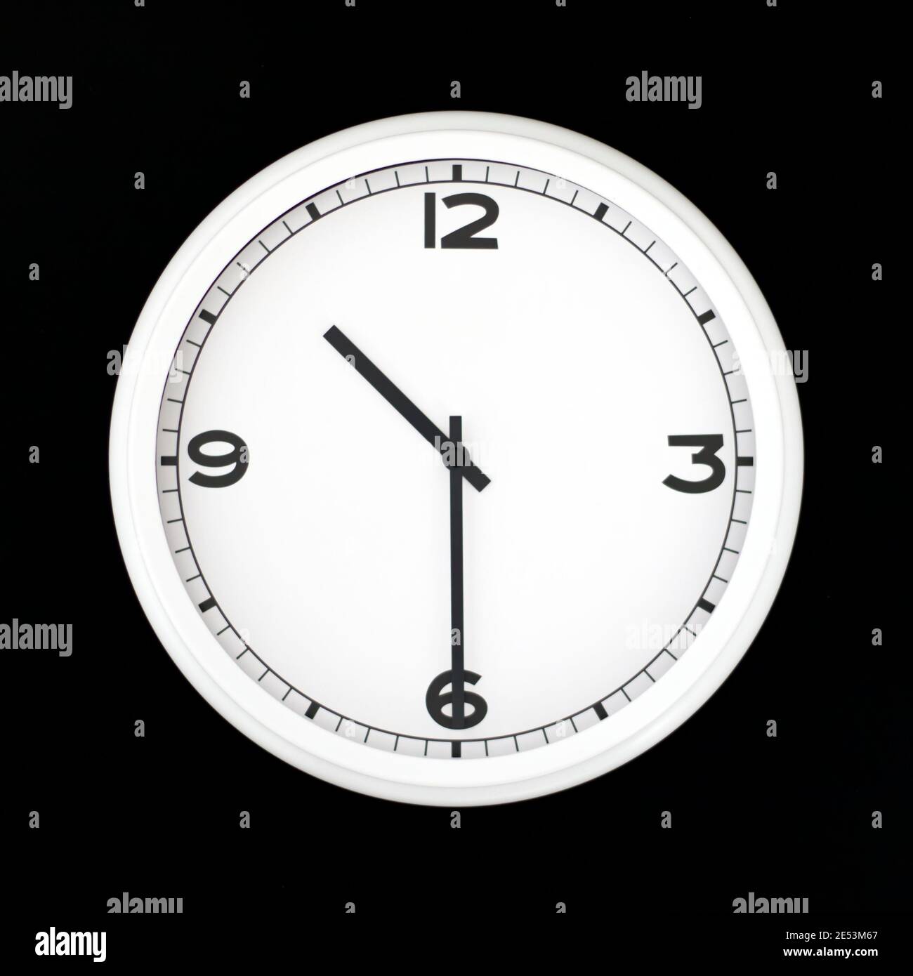 White round analog wall clock isolated on black background, its half ...