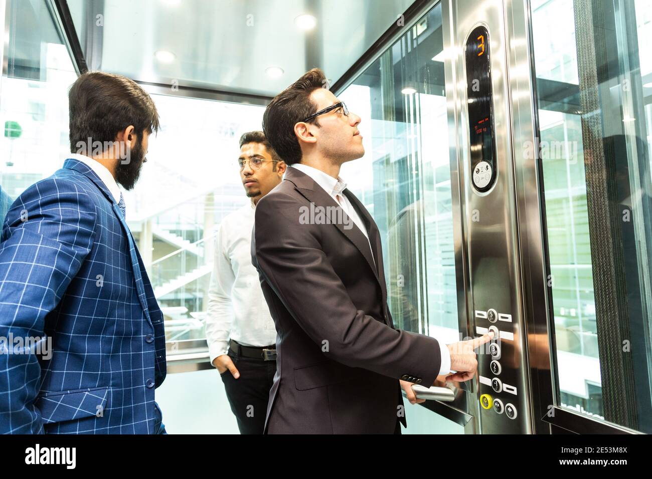 Business team group going on elevator. Business people in a large glass ...