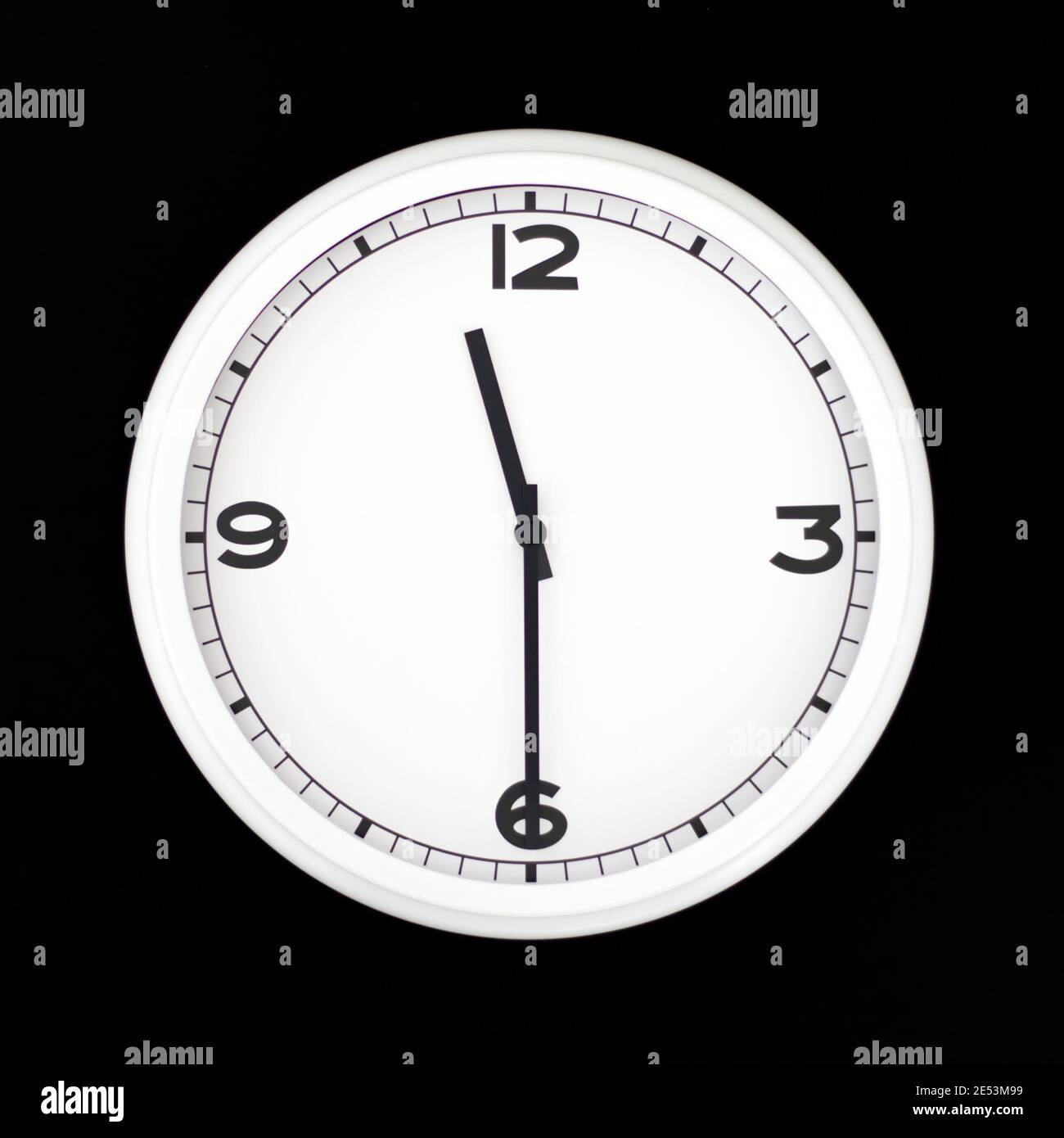 White round analog wall clock isolated on black background, its half ...