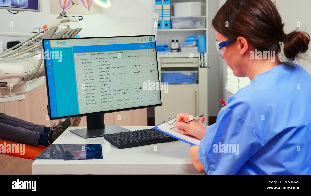 Orthodontist nurse looking at list with appointments in computer and ...