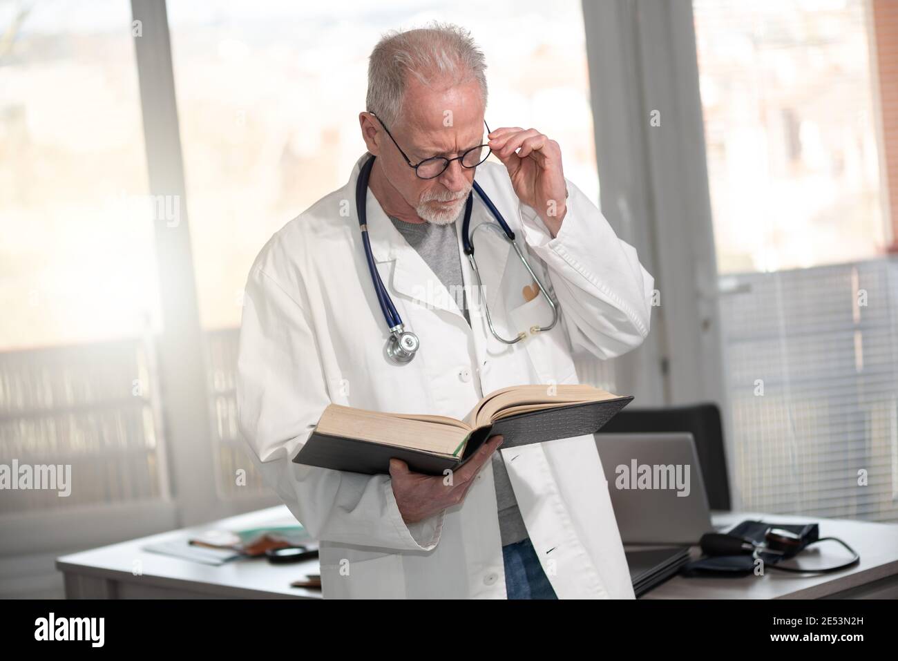 Senior doctor reading a textbook in clinic Stock Photo - Alamy