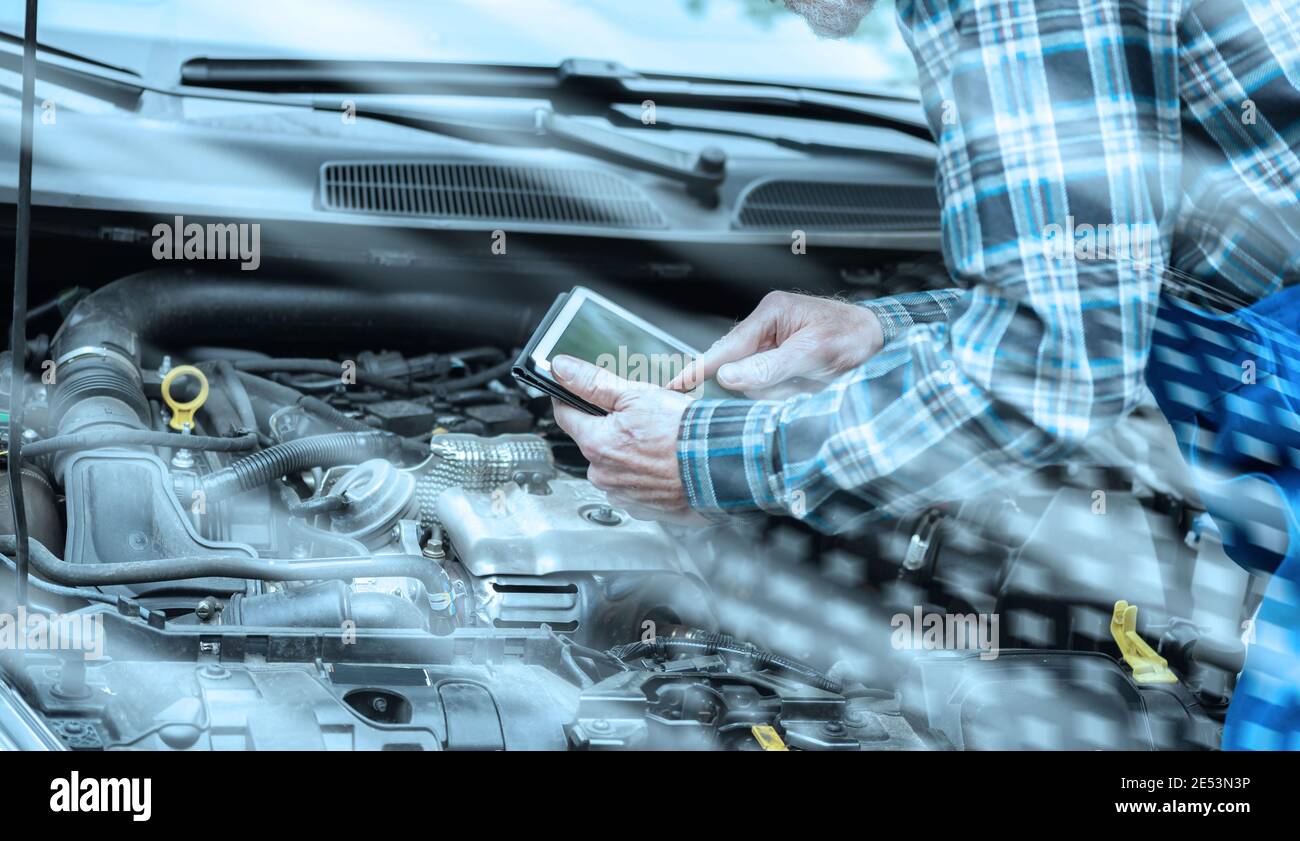 Car mechanic using digital tablet for checking car engine; light effect ...