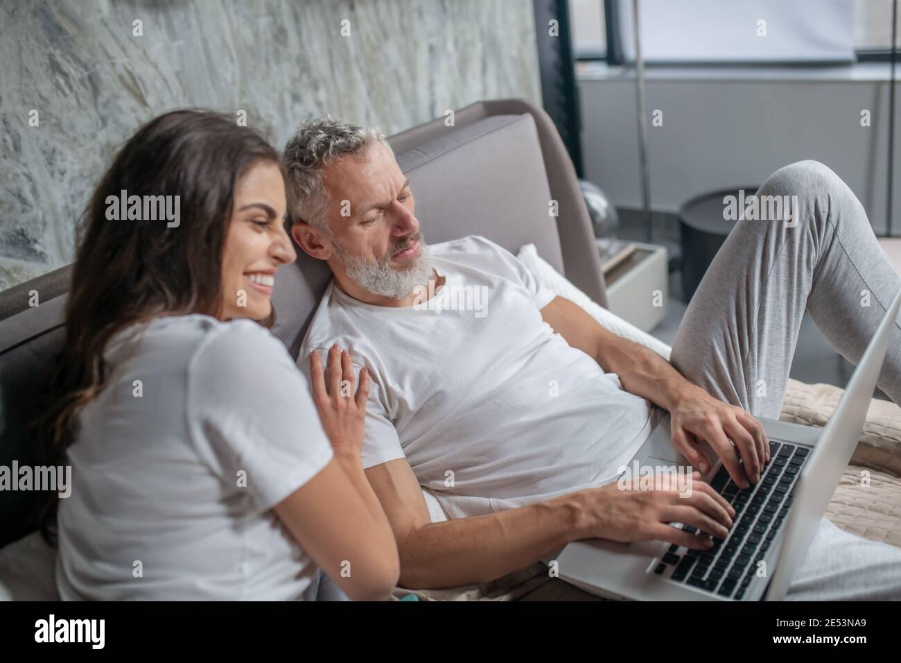Husband typing on laptop keyboard and joyful wife Stock Photo - Alamy