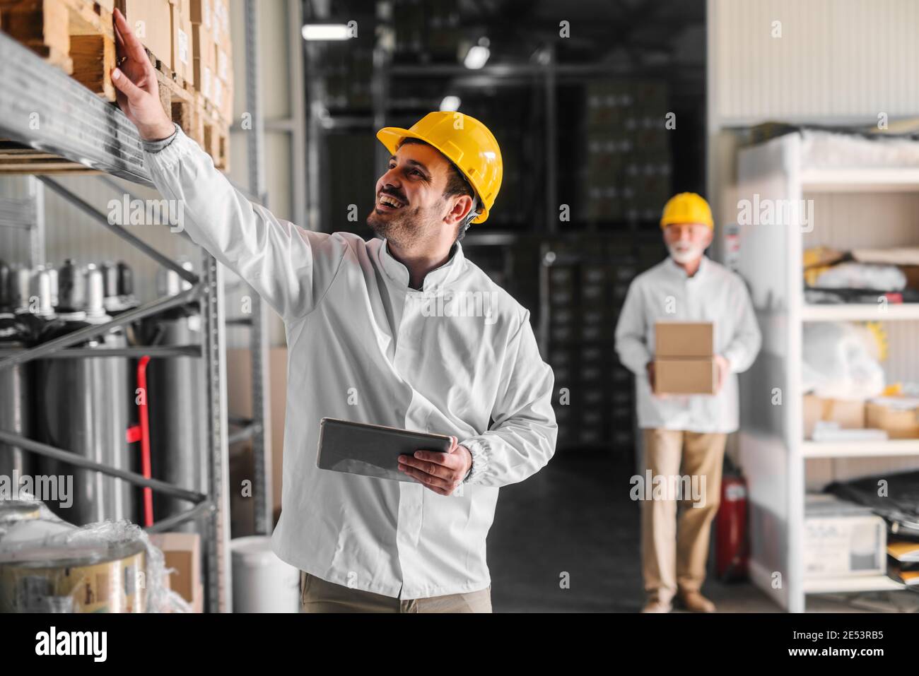 Picture of smiling young man warehouse worker counting boxes in ...