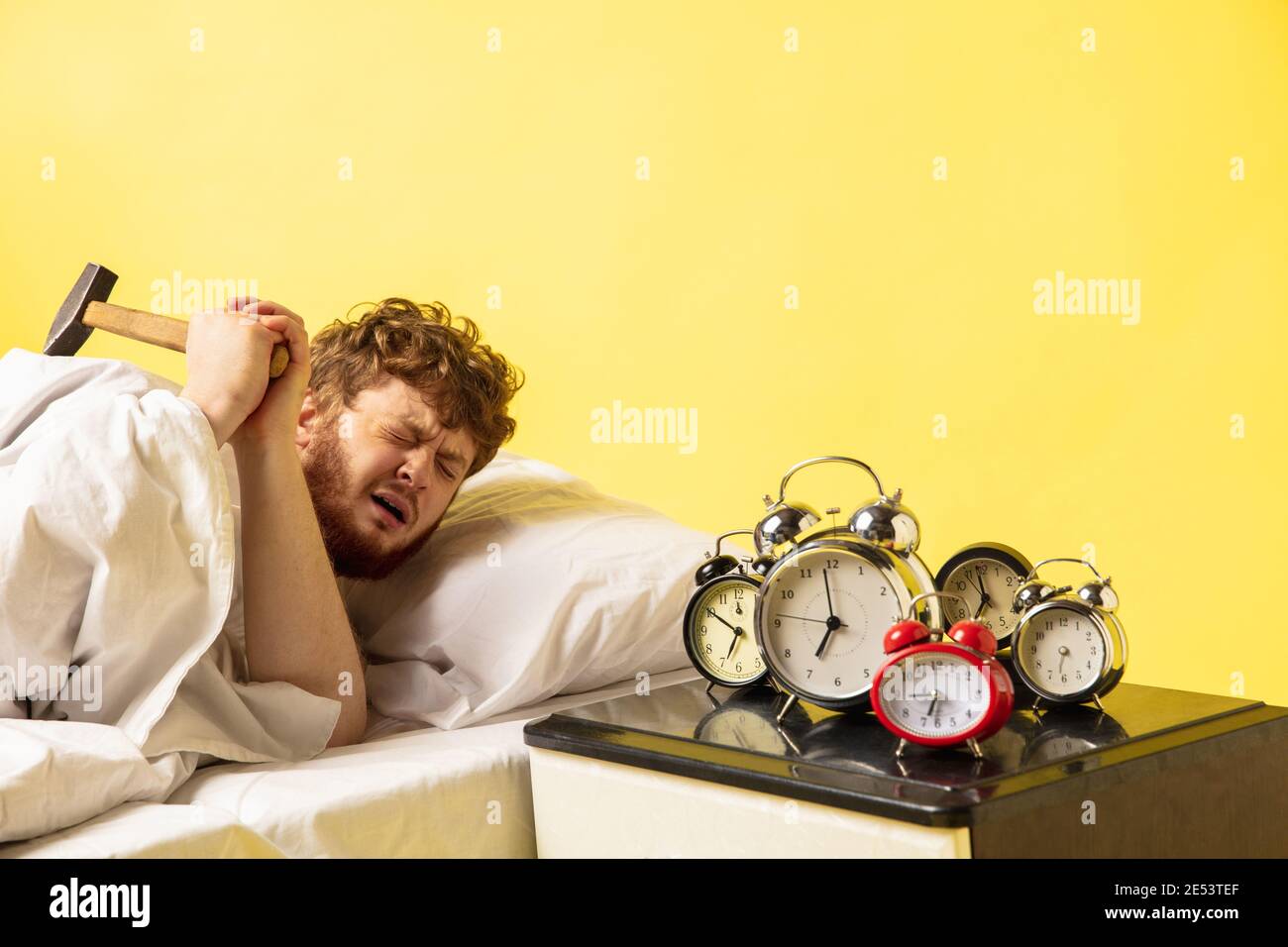 Painful. Man wakes up at his bed on yellow background and he's mad at ...