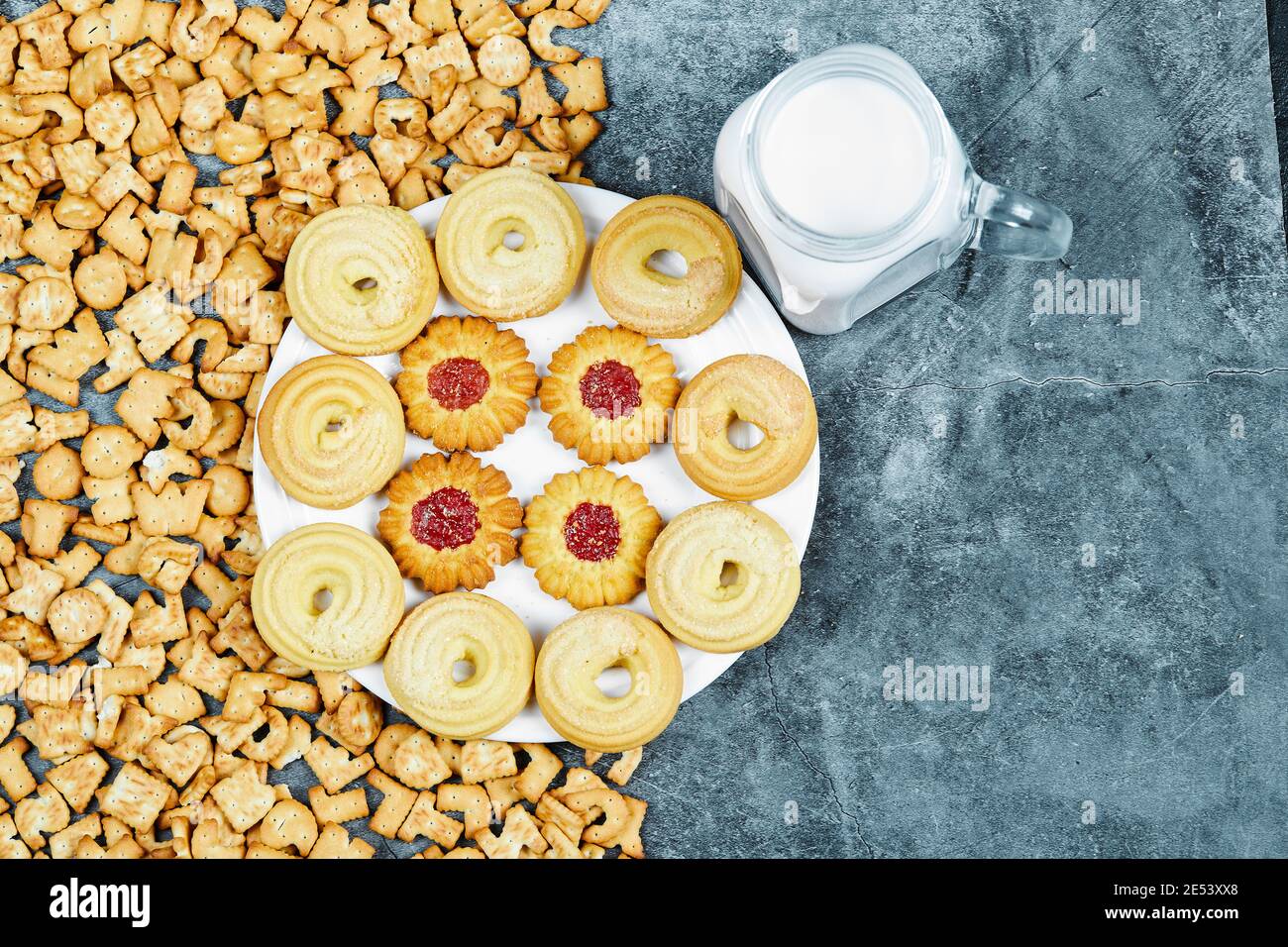 Scattered alphabet crackers, a plate of cookies and a jar of milk on ...