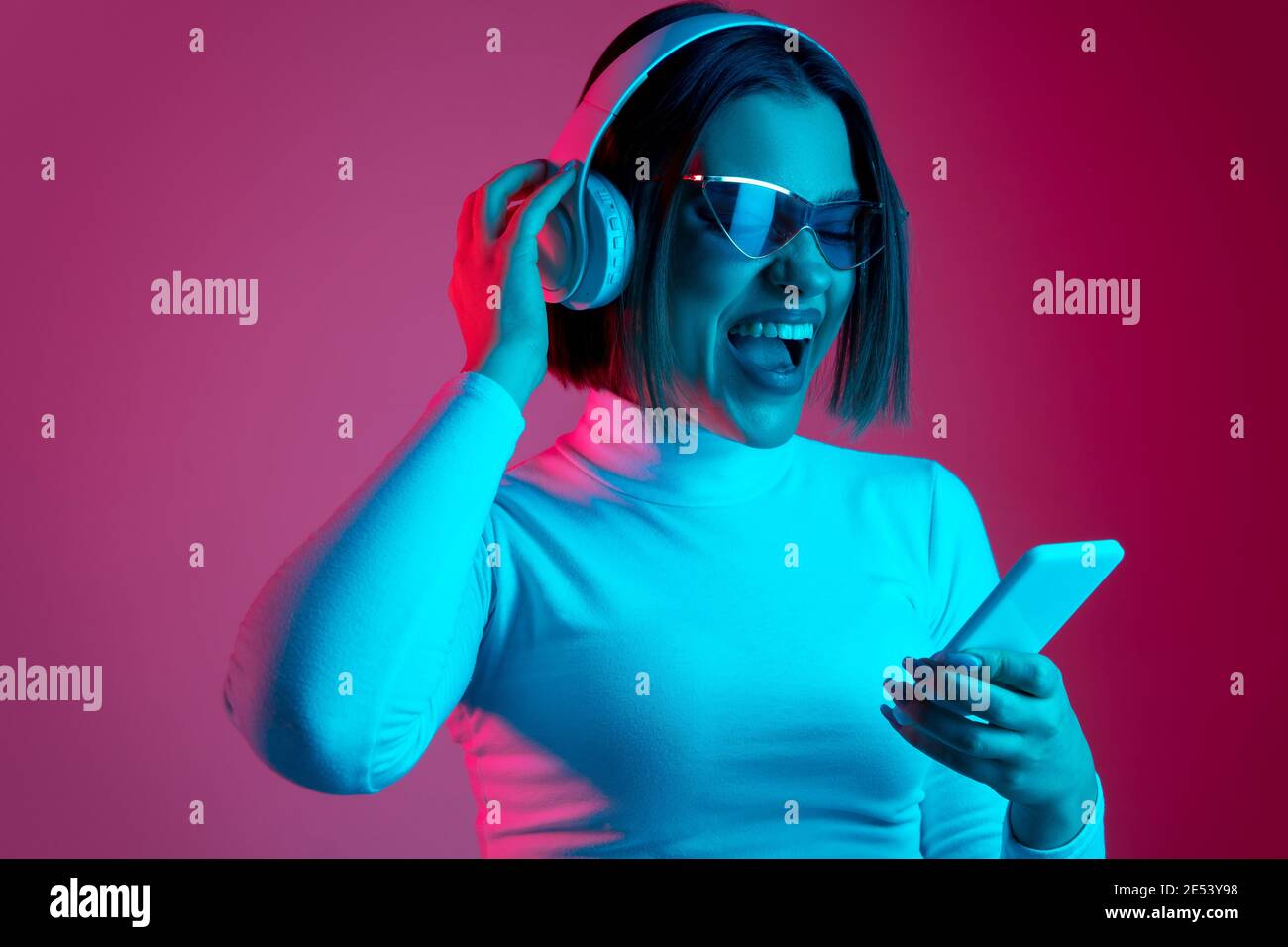 Shocked. Caucasian woman's portrait on pink studio background in red ...