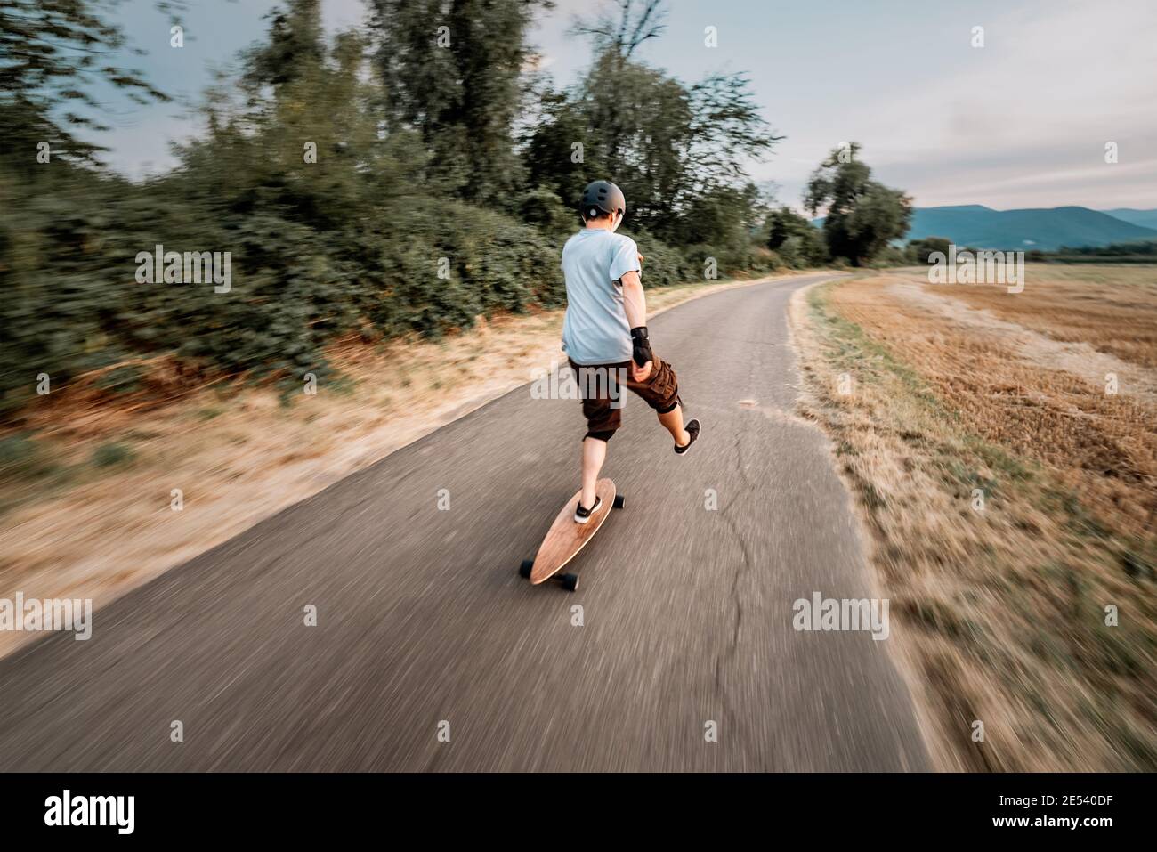 the man is riding a longboard down the street Stock Photo - Alamy