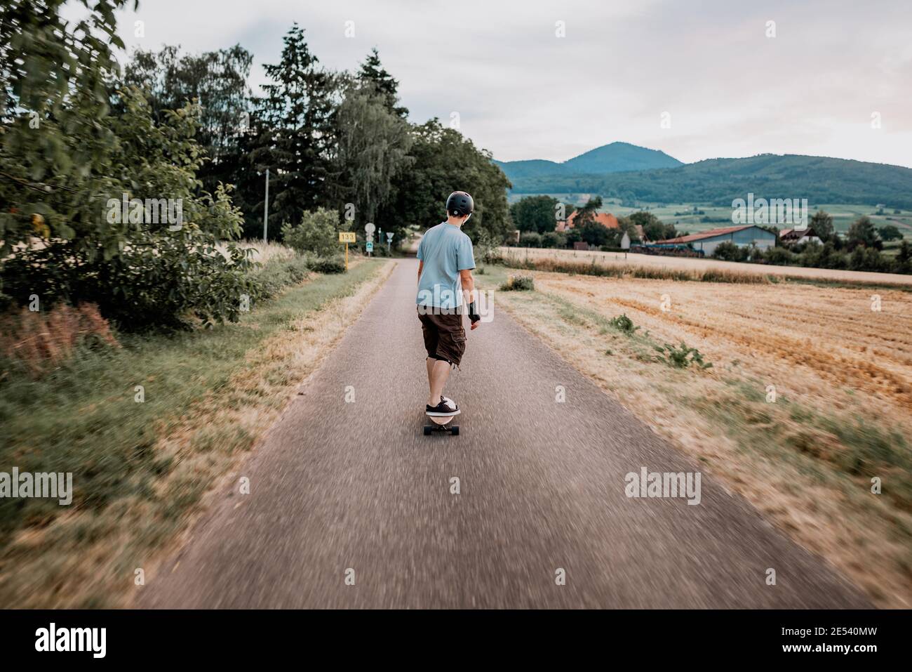 the man is riding a longboard down the street Stock Photo - Alamy
