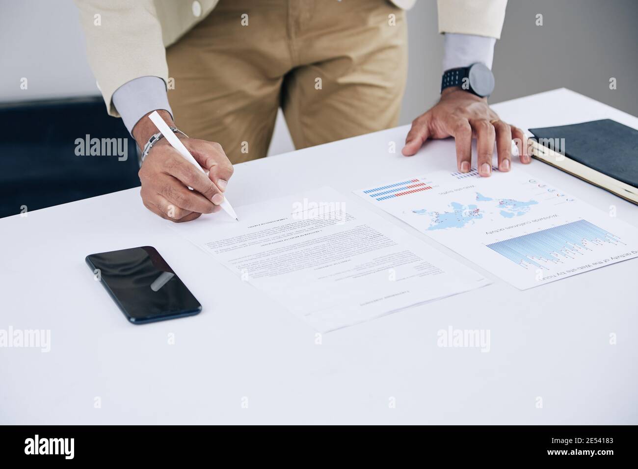 Businessman standing at desk, checking chart and reading financial ...