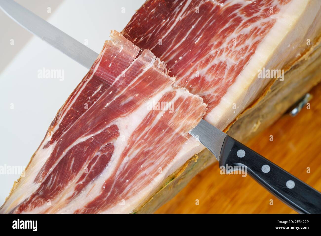 Cut of acorn-fed Iberian ham on metal and wood ham holder, typical ...