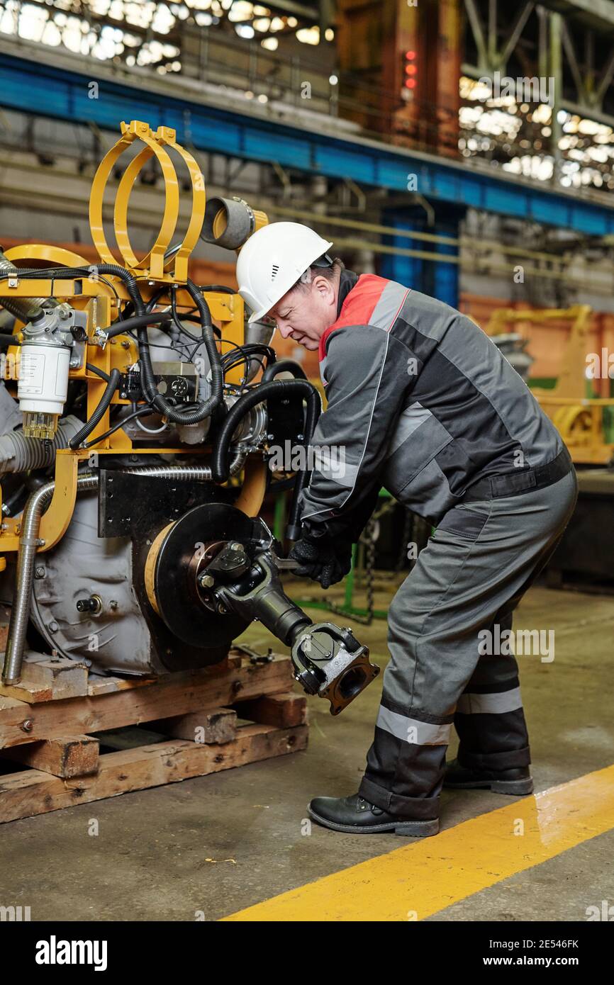 Mature engineer in workwear working with metal equipment in the ...