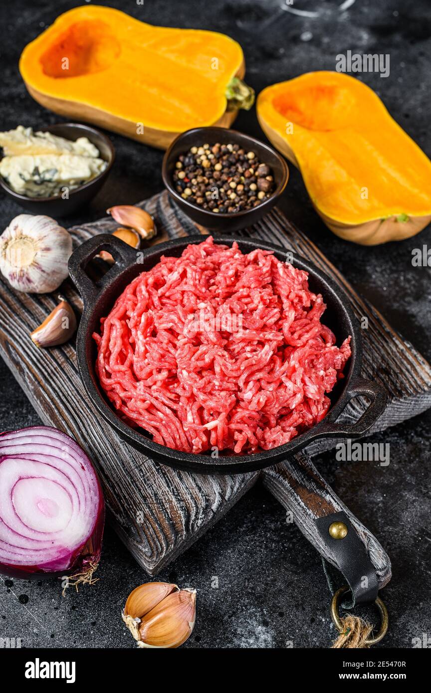 Raw mince meat, pumpkin with garlic and onion. Black background. Top ...