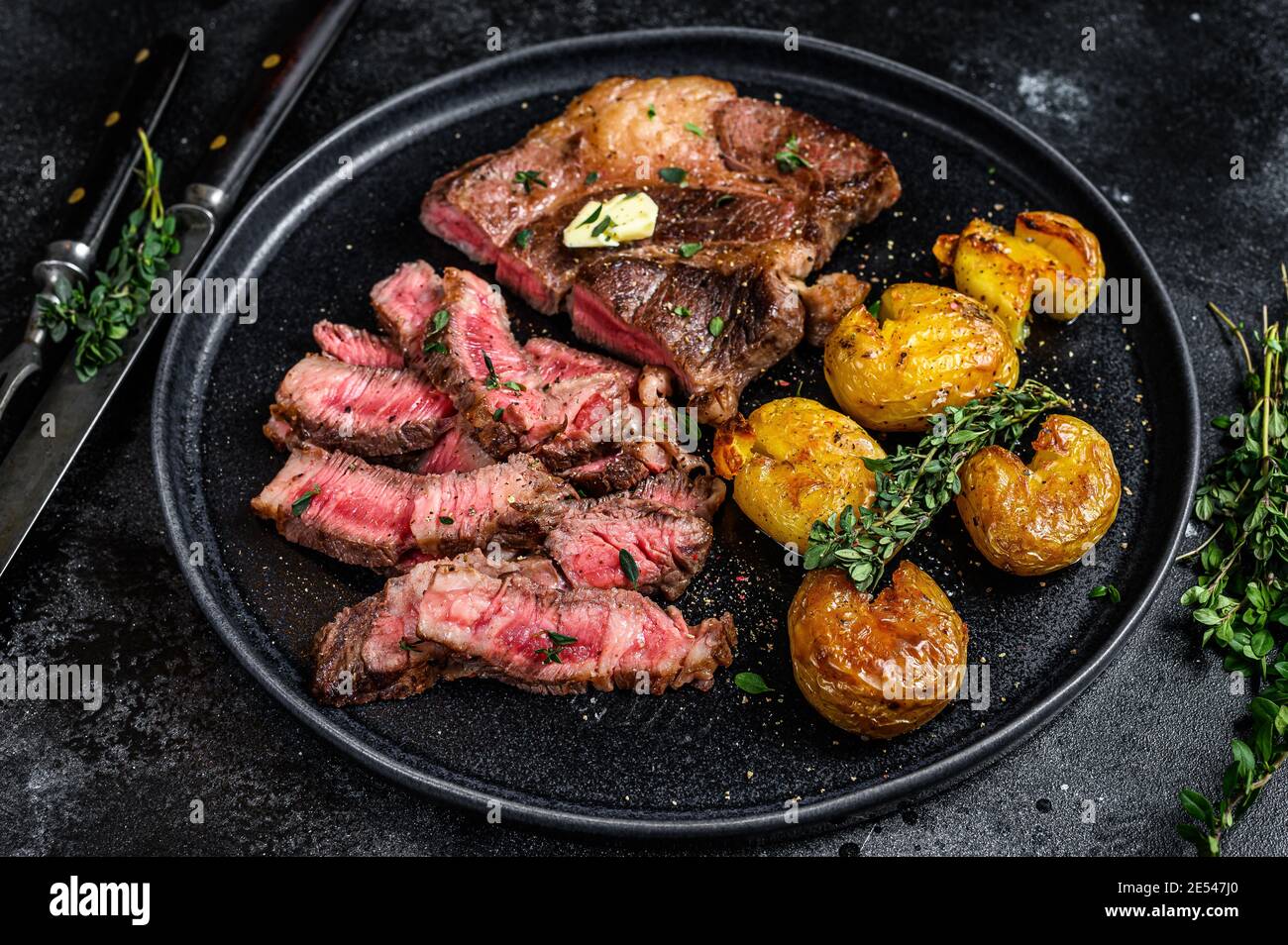 Cut Grilled rib eye beef meat steak with potato. Black background. Top ...