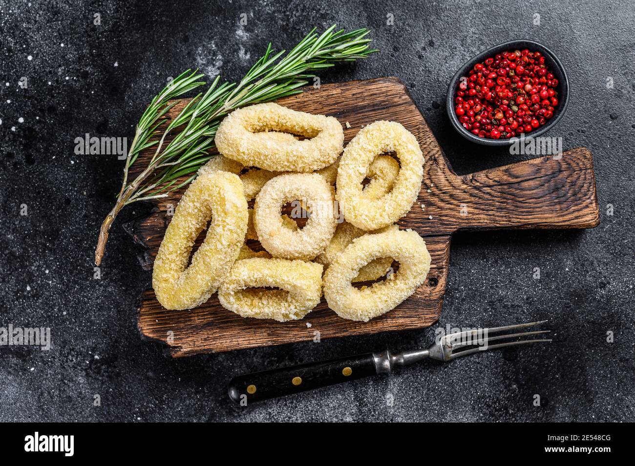 Raw crispy squid rings in breadcrumbs on a cutting board. Black ...