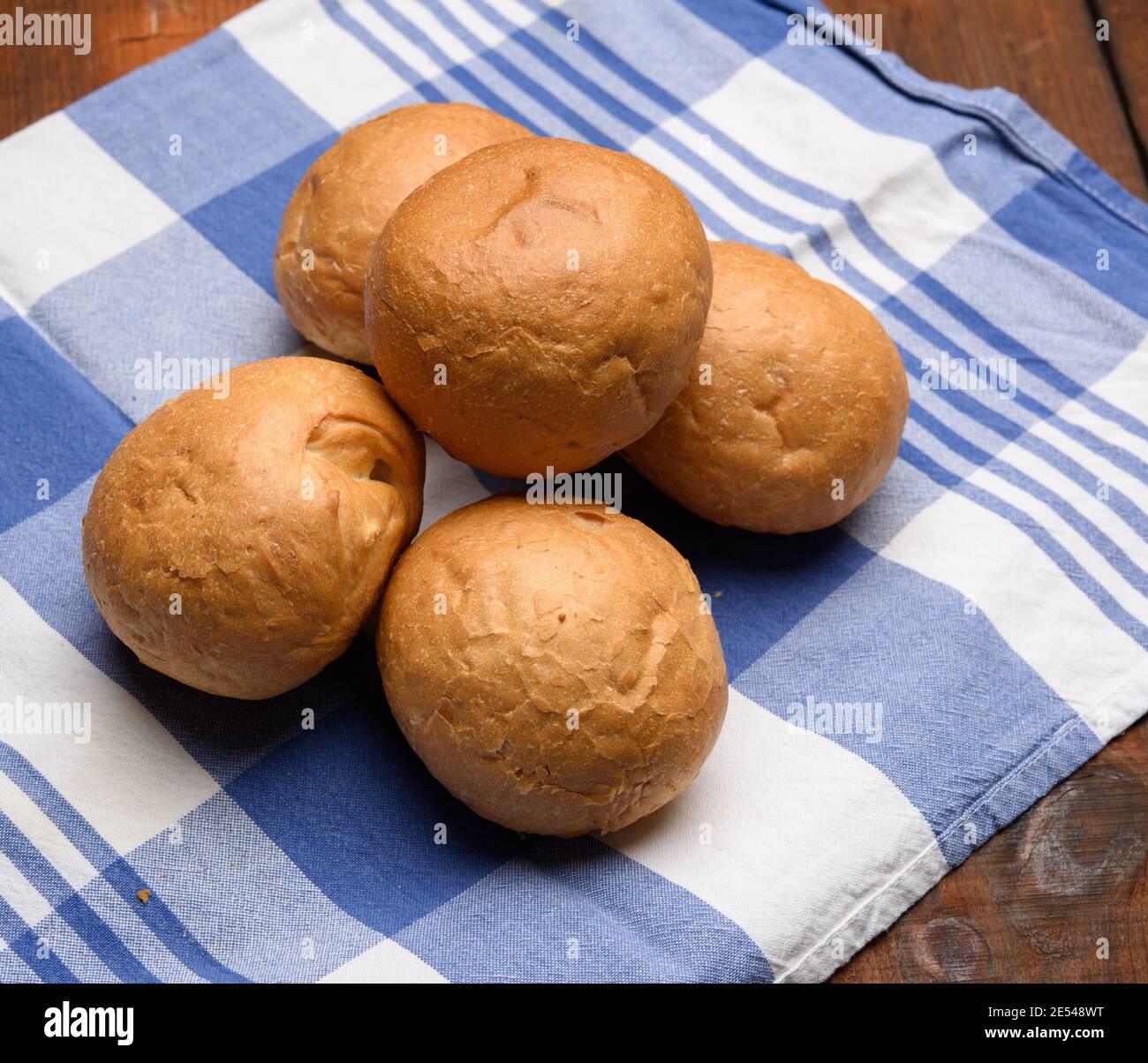 baked round small buns on a brown wooden table, close up Stock Photo ...