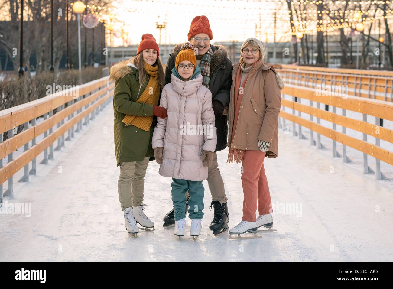 Portrait of happy family smiling at camera while standing on ice rink ...