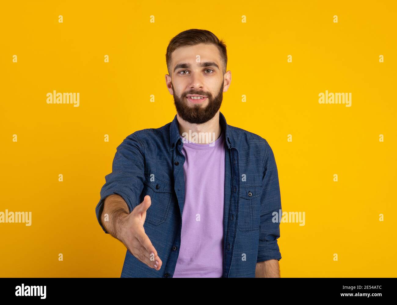 Greeting concept. Smiling Caucasian guy holding out his hand for ...