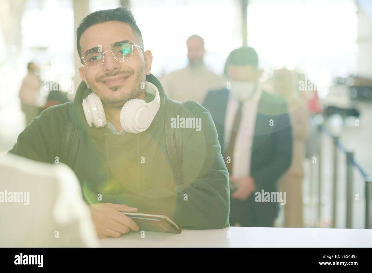 Young man smiling to airport worker while standing at reception desk at ...