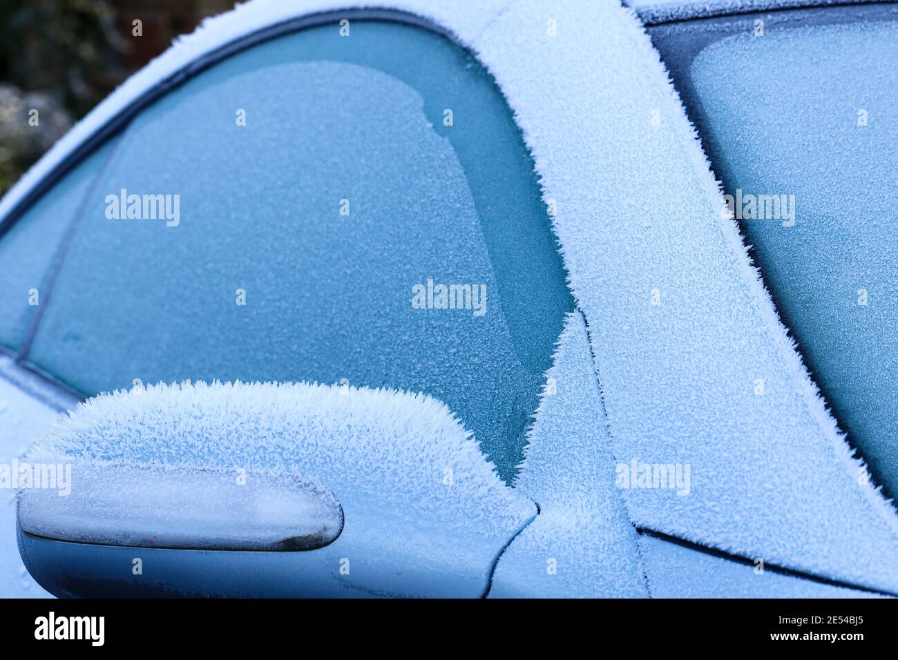 Side profile and close up of a car window covered with thick frost and ...
