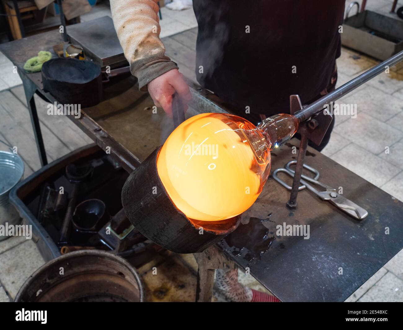 Man Hands Shaping hot glass art piece with wooden tool. Traditional ...