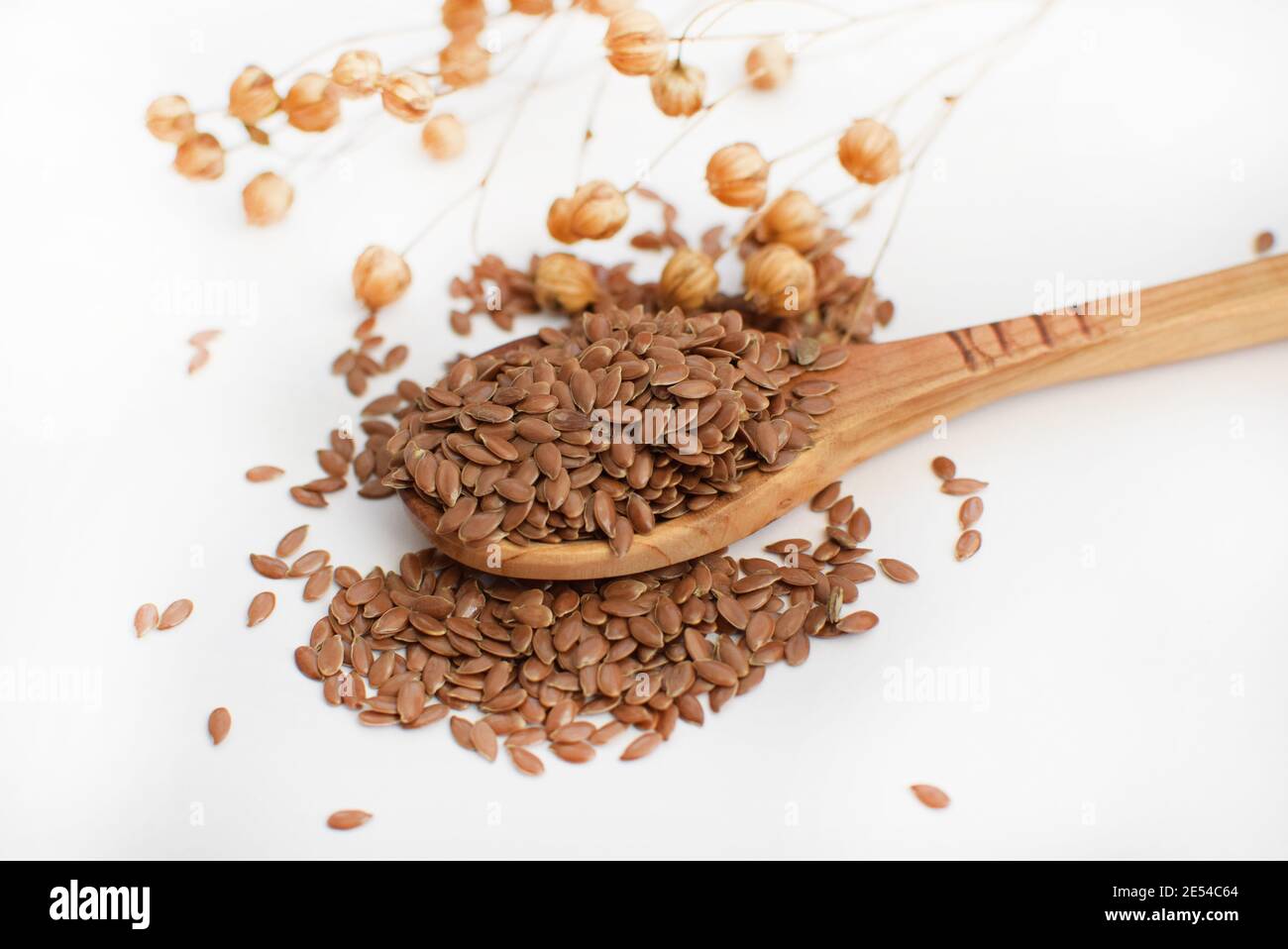 Flax seeds in a wooden spoon. Flax seeds and linseed bolls on a white background. Healthy food ...