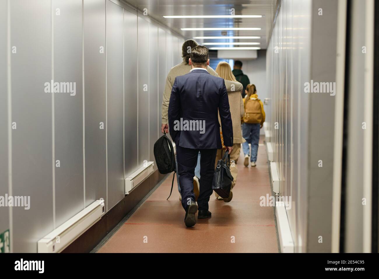 Rear view of people going along the corridor of airport terminal for ...