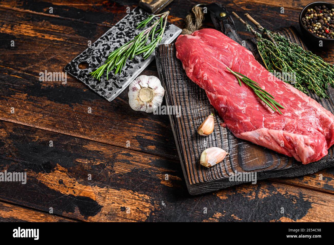 Raw skirt machete beef meat steak on a cutting board with cleaver. Dark ...