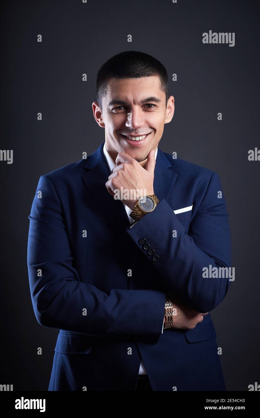 Portrait of a businessman in blue jacket on dark background in studio ...