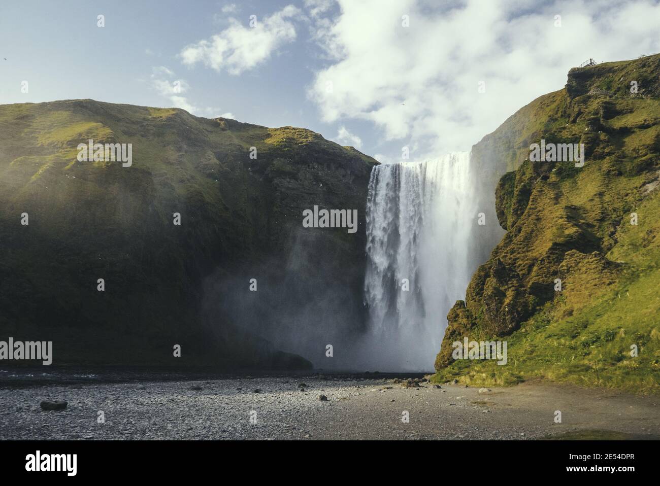 Beautiful scenery of a high waterfall with green cliffs, water steam ...