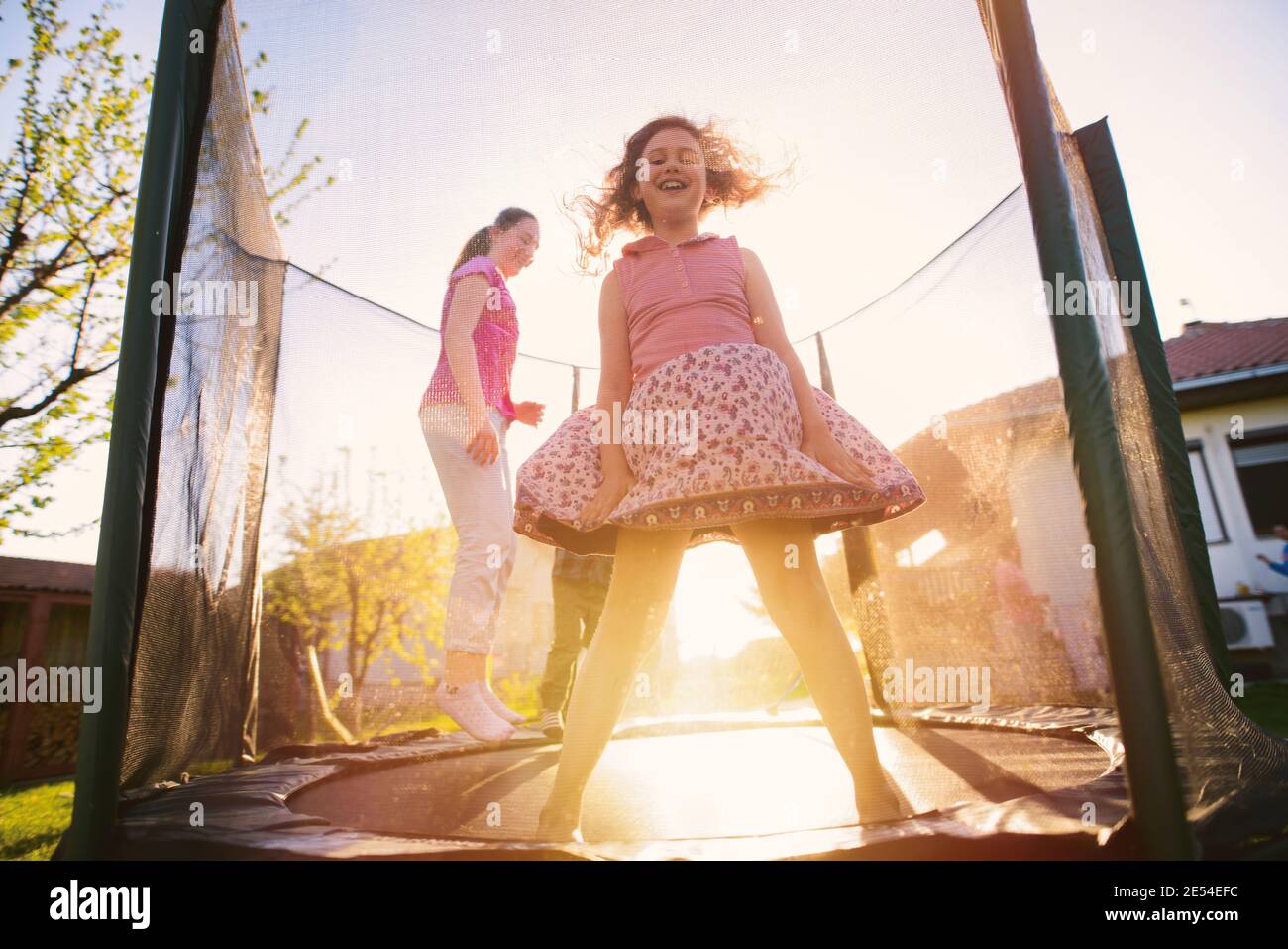 Cheerful happy kids having fun and jumping in a trampoline on a sunny ...