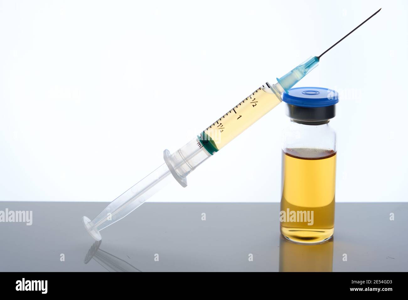 Medical vial vaccine dose and syringe on mirror surface, white backdrop ...