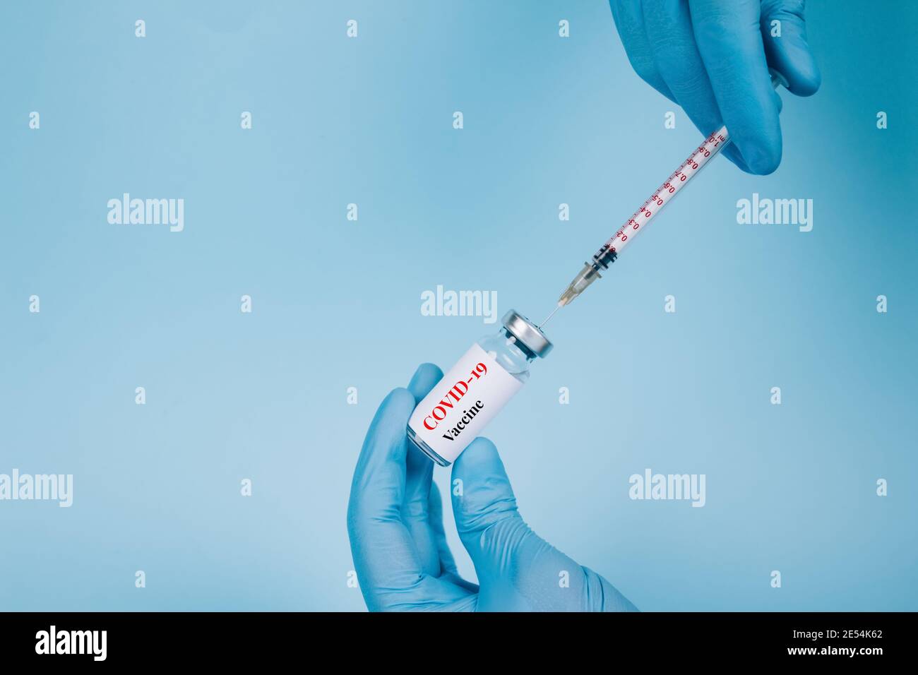 Doctor injecting vial dose of COVID-19 vaccine with syringe against ...