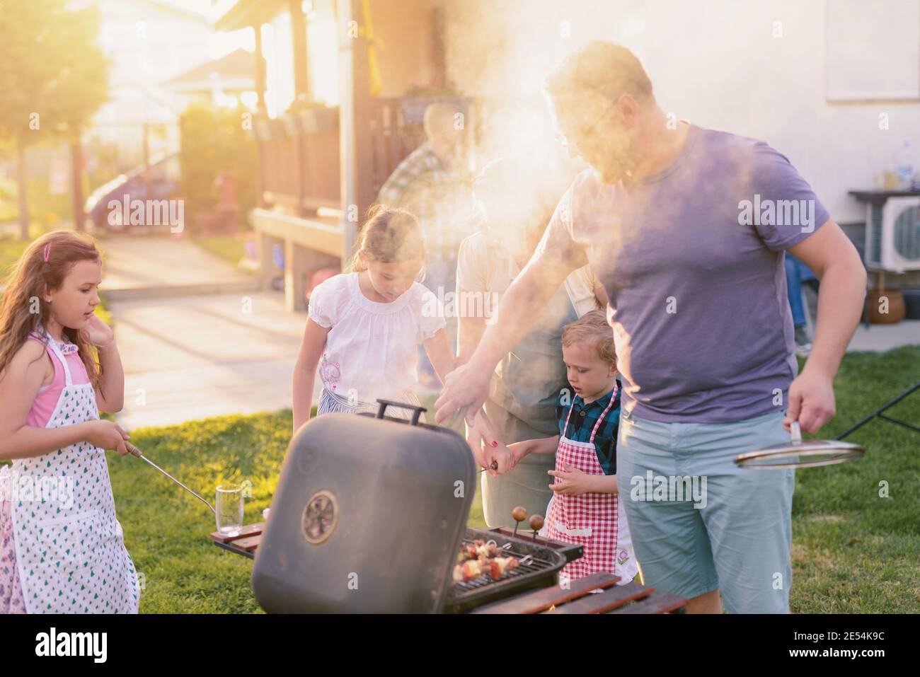 Proud happy father making barbeque for his family in backyard. Standing ...