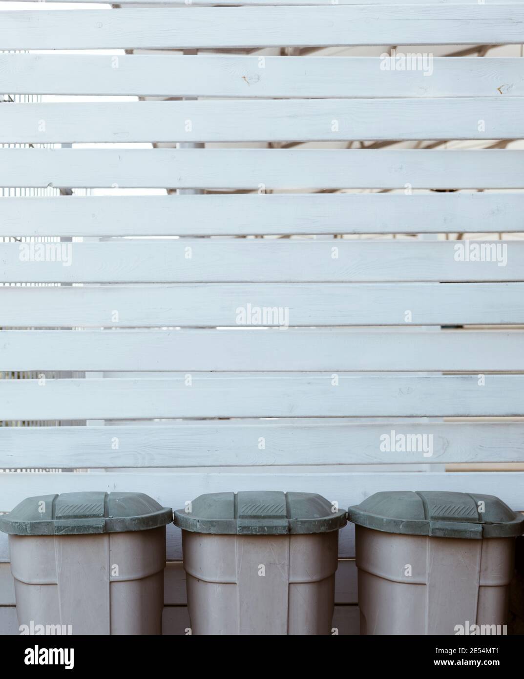 White wooden planks background with three plastic garbage trash bins ...