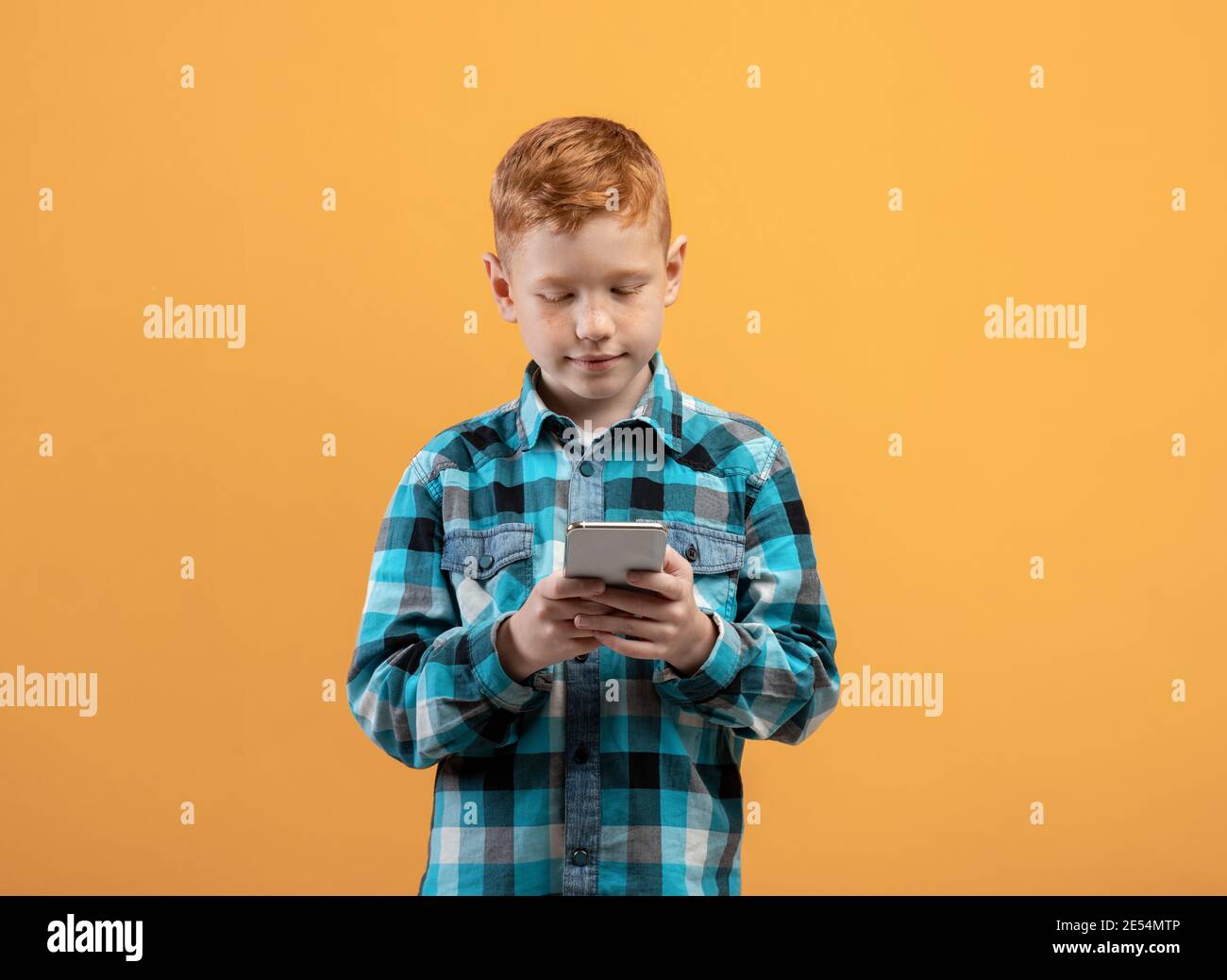 Cute ginger kid with mobile phone on yellow Stock Photo - Alamy