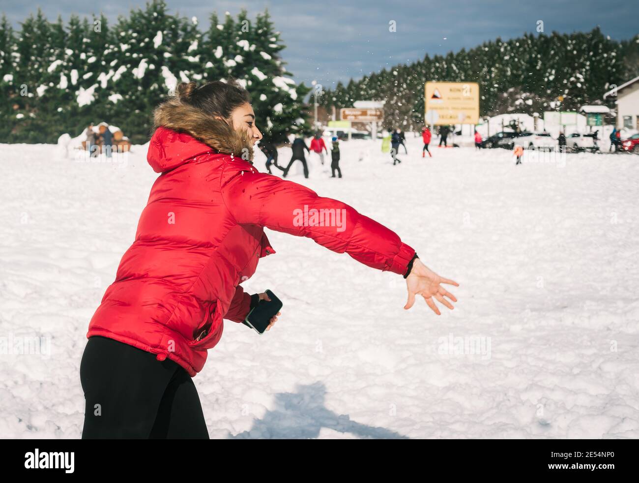 Caucasian female throwing snowballs while wearing a red jacket Stock ...