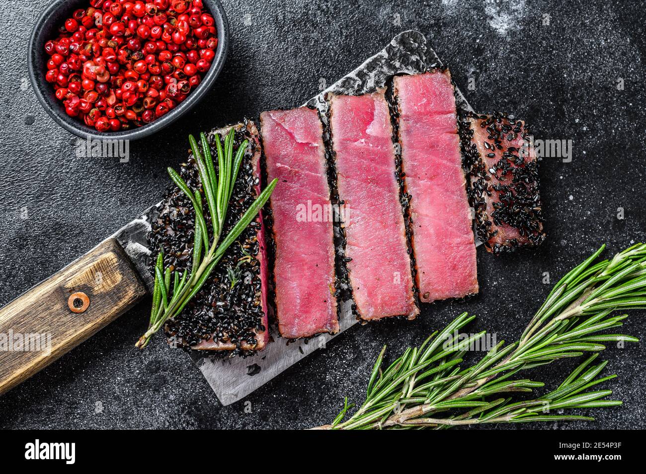 Rare Ahi tuna steak slices on a meat cleaver. Black background. Top ...