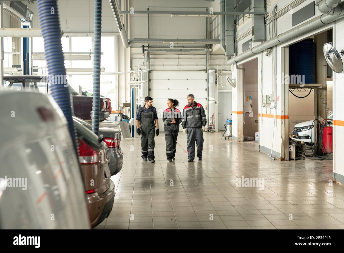 Three intercultural male and female workers of car maintenance center ...