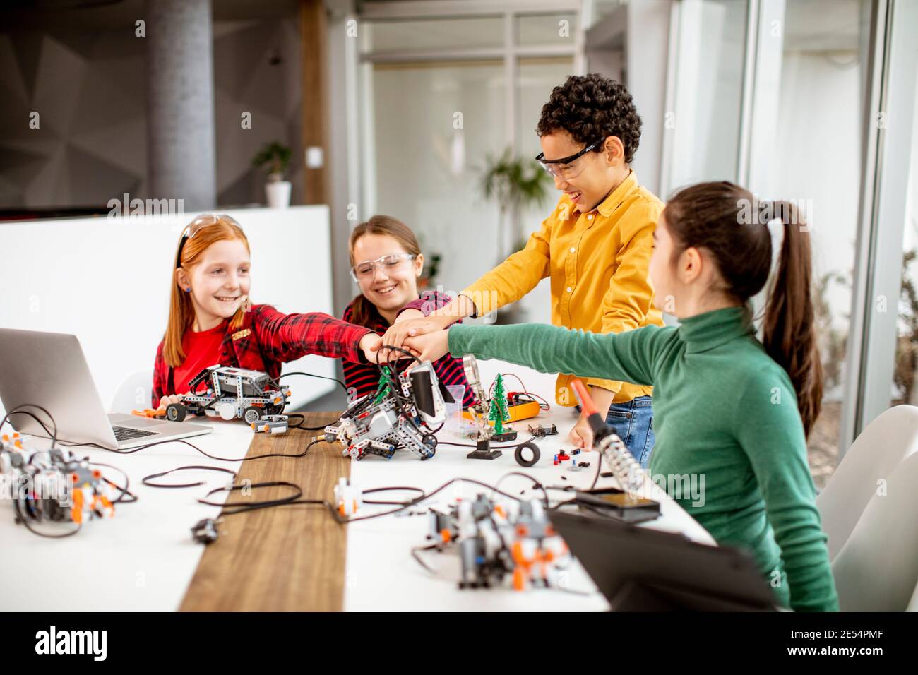 Group of happy kids programming electric toys and robots at robotics ...