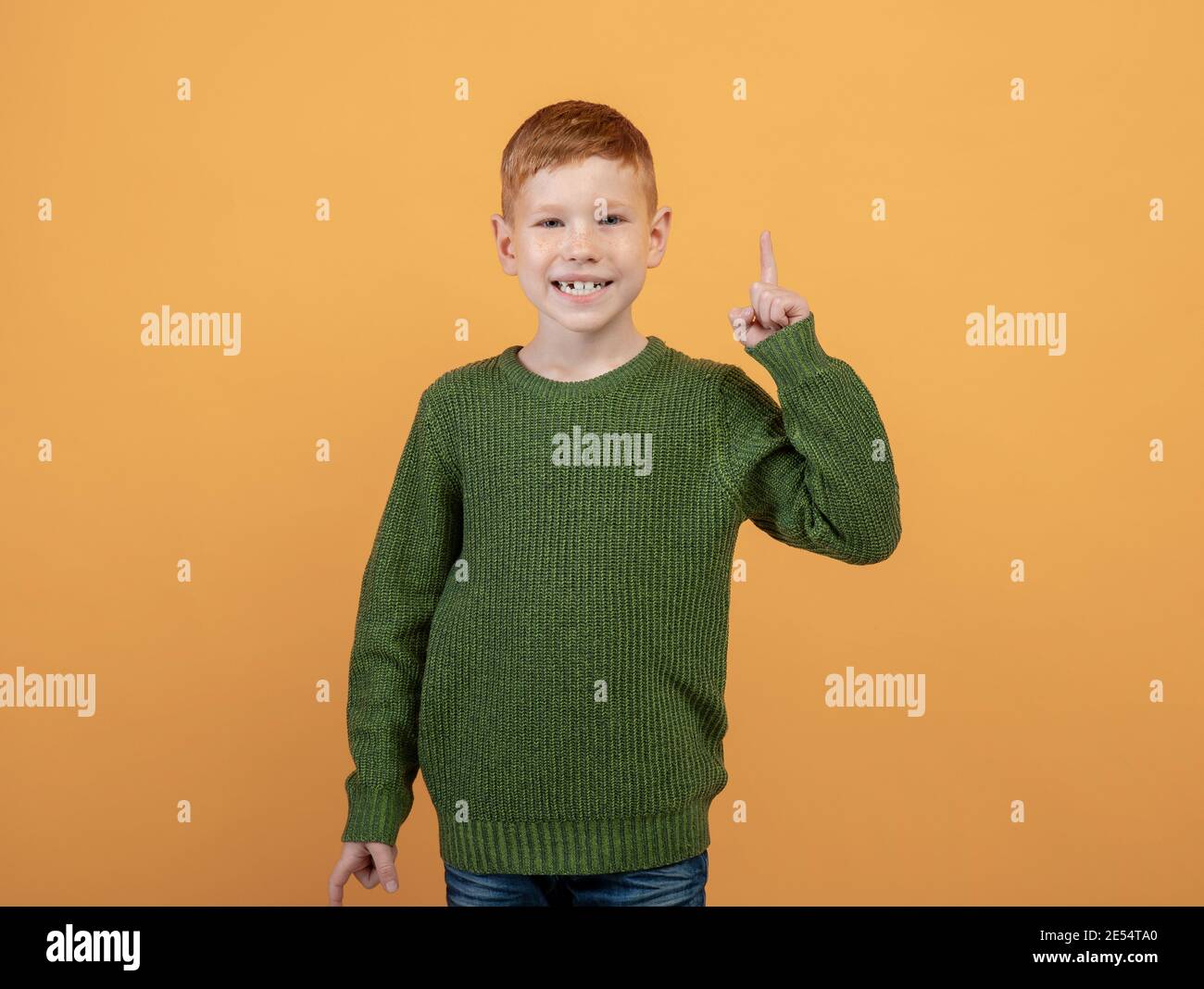Happy ginger kid in knitted sweater pointing finger up Stock Photo - Alamy